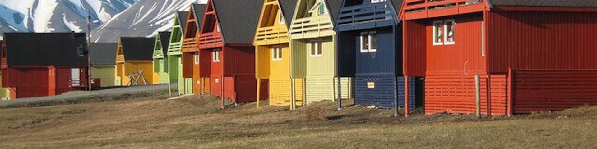 Casas de madeira coloridas com montanhas cobertas de neve ao fundo.