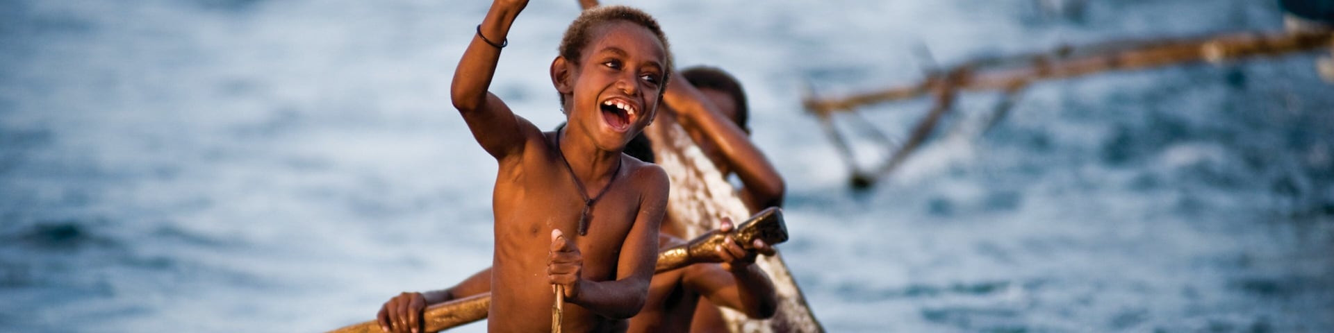Uma pessoa remando um barco de madeira na água.