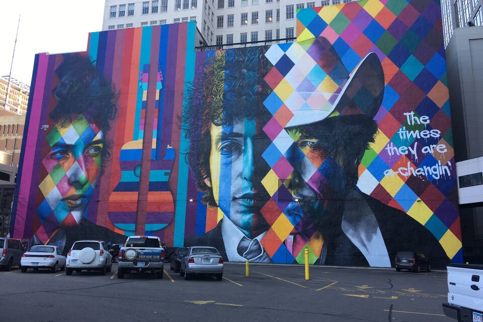 Um mural colorido com padrões de diamantes e uma citação em um edifício.