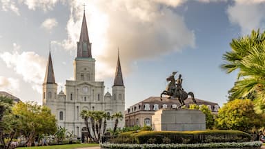 Uma igreja histórica com três torres e uma estátua de um homem montado a cavalo.