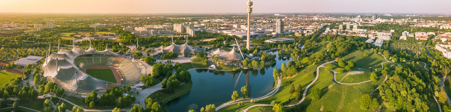 Paisagem urbana com uma torre imponente, um estádio e áreas verdes ao redor.
