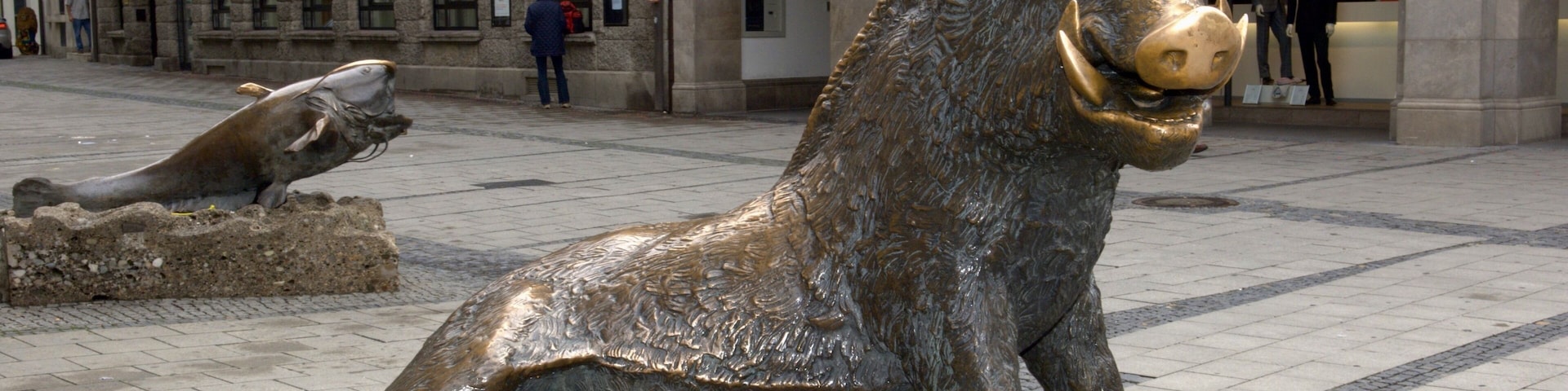 "Sitting wild boar" by sculptor Martin Mayer in Munich. In the area between Marienplatz and Karlsplatz a pig is sitting in front of a church. The sculptures were done for the German Hunting and Fishing Museum. The bronze boar by Martin Mayer has been sitting in front of the museum since 1976.