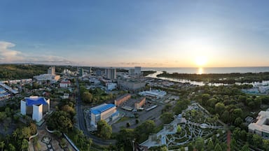 Paisagem costeira ao pôr do sol com um rio, edifícios e um parque.