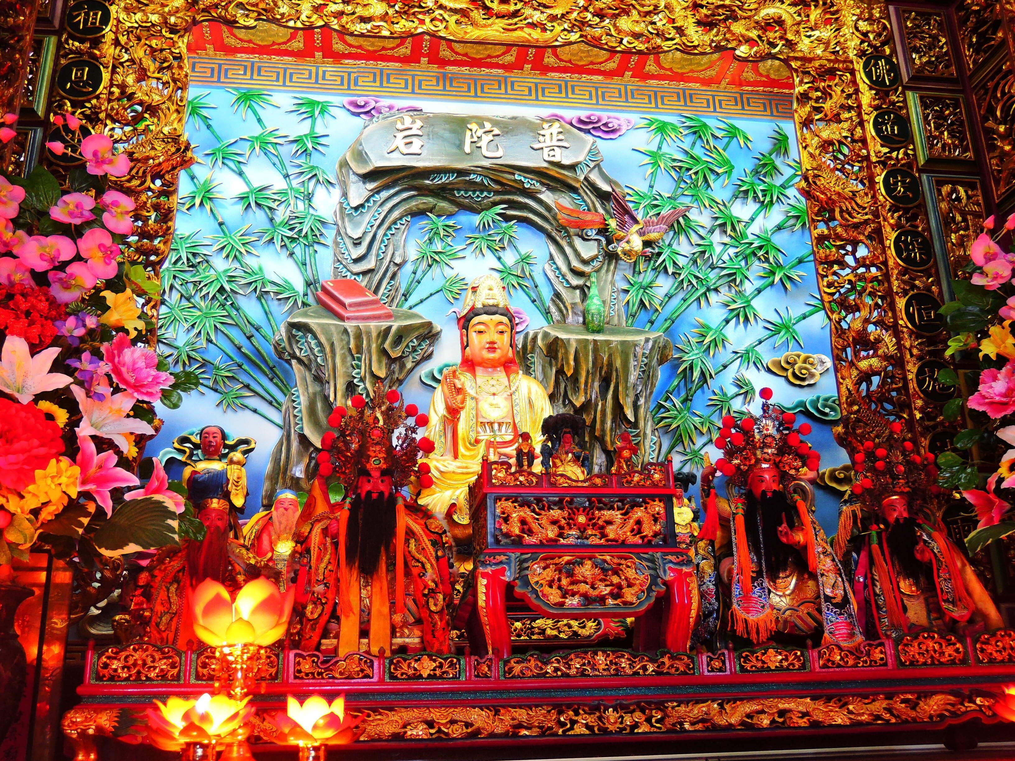 Um santuário ricamente decorado com uma estátua central, rodeado por esculturas detalhadas e vibrantes arranjos florais.