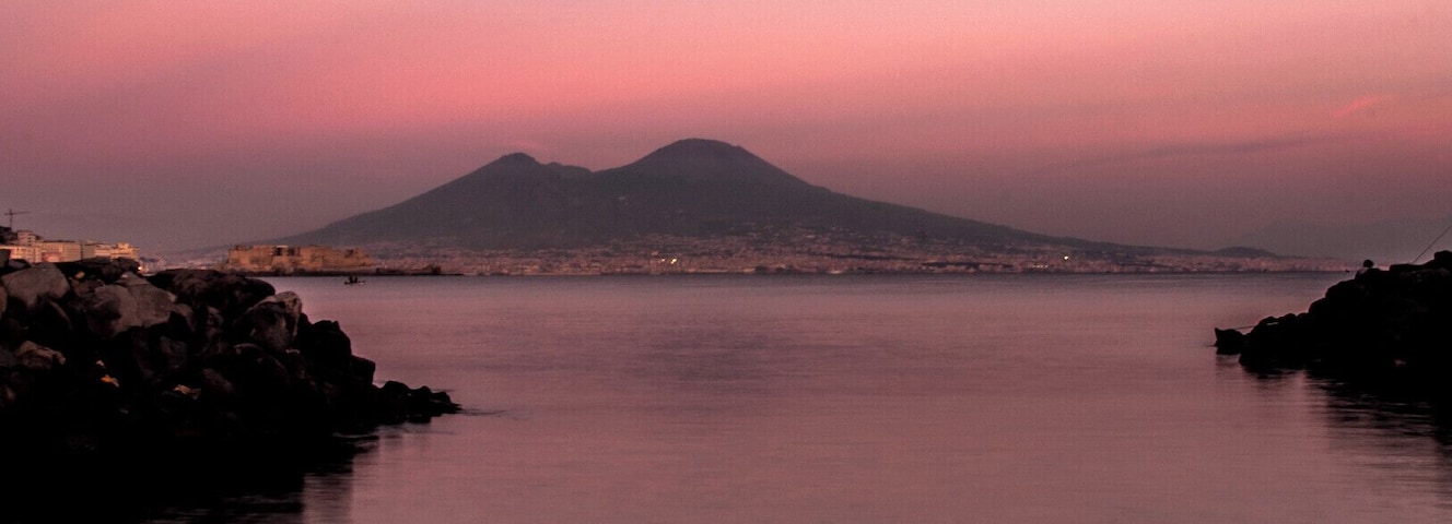 Água calma refletindo o céu, com uma montanha ao longe e uma lua crescente visível.