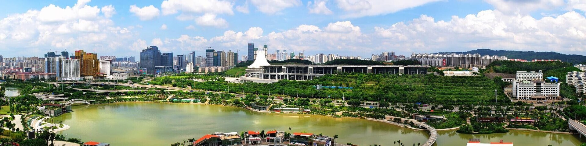 Paisagem urbana com um grande lago, edifícios modernos e uma estrutura branca marcante.