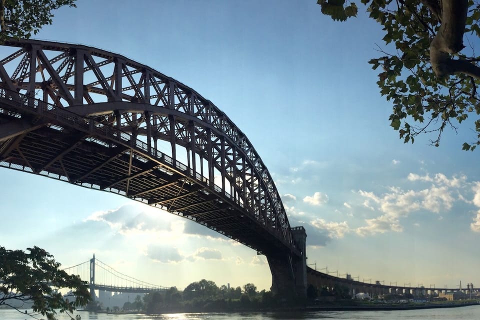 Uma ponte de aço sobre um rio, com céu claro e algumas nuvens.