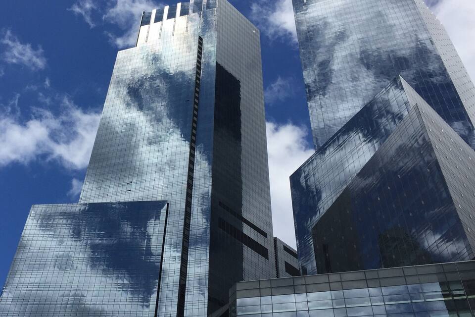 Um conjunto de arranha-céus modernos com fachadas de vidro refletivo sob um céu parcialmente nublado.