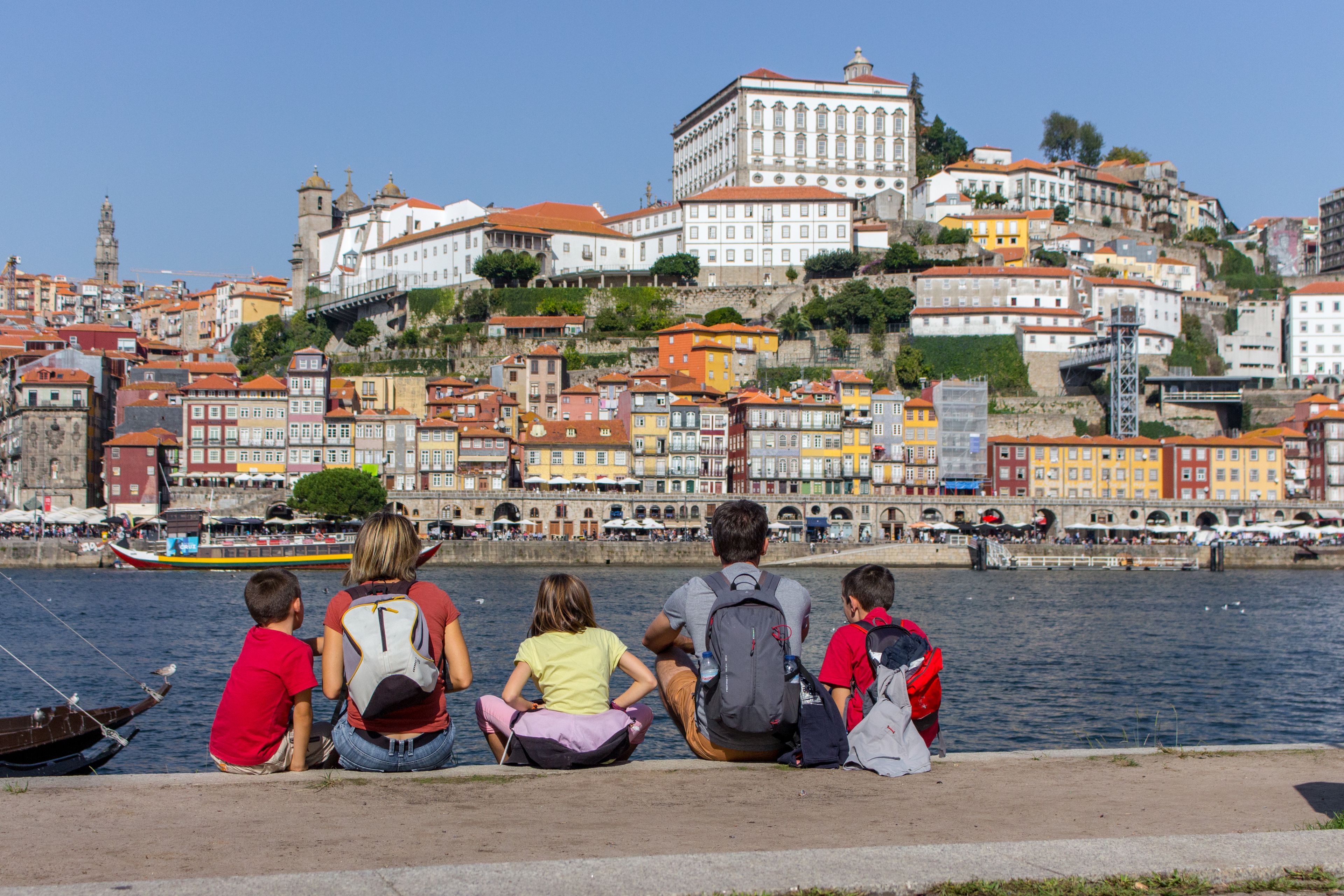 Um grupo de pessoas sentadas à beira-mar, com um centro histórico como pano de fundo.