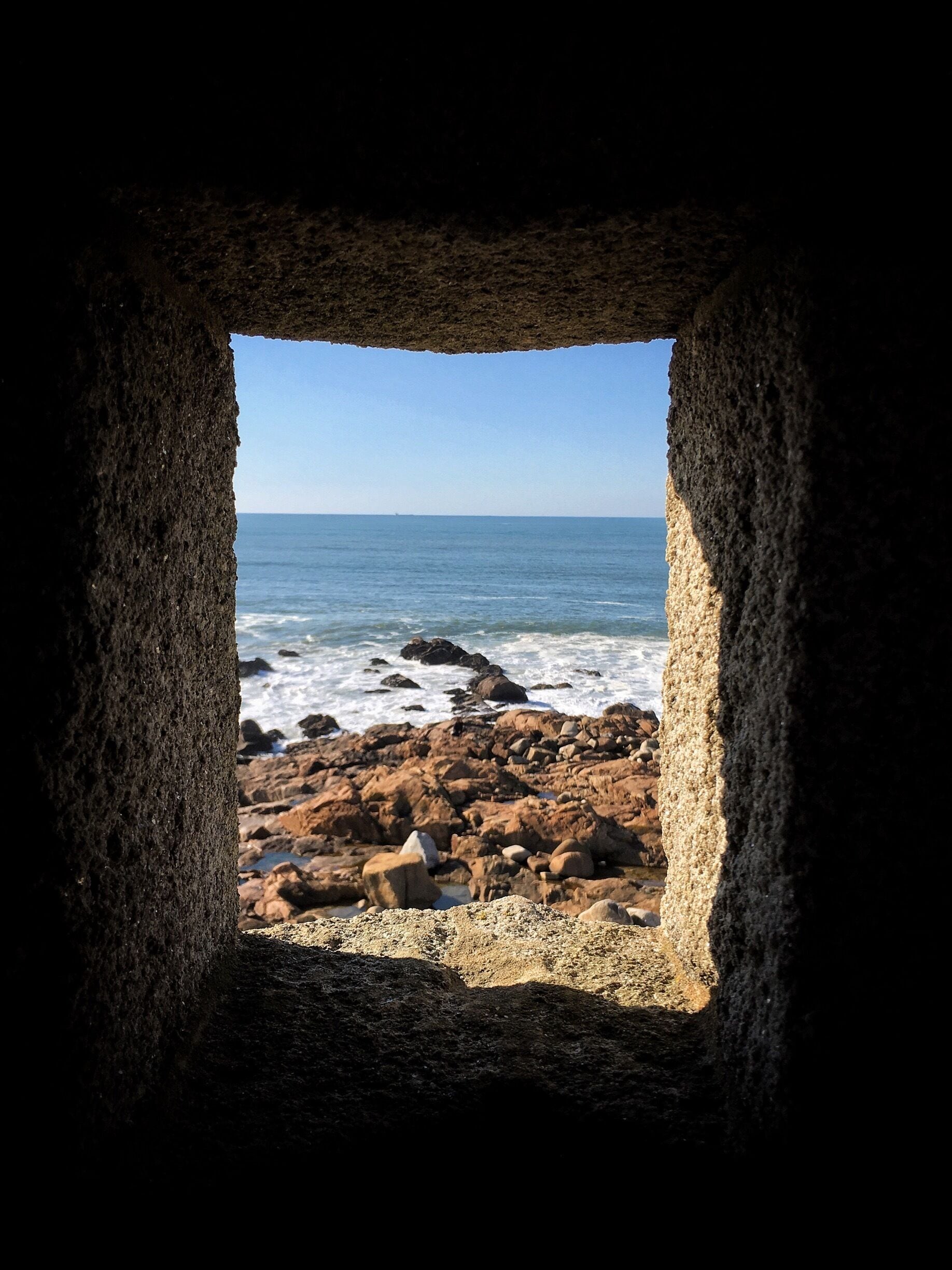 Uma costa rochosa com ondas quebrando nas pedras.