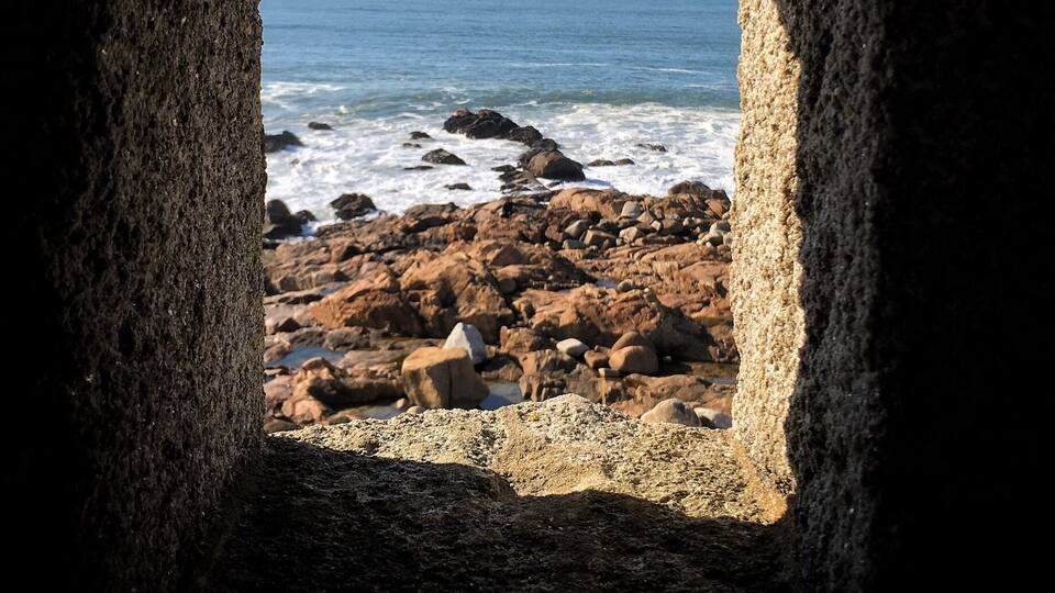 Uma costa rochosa com ondas quebrando nas pedras.