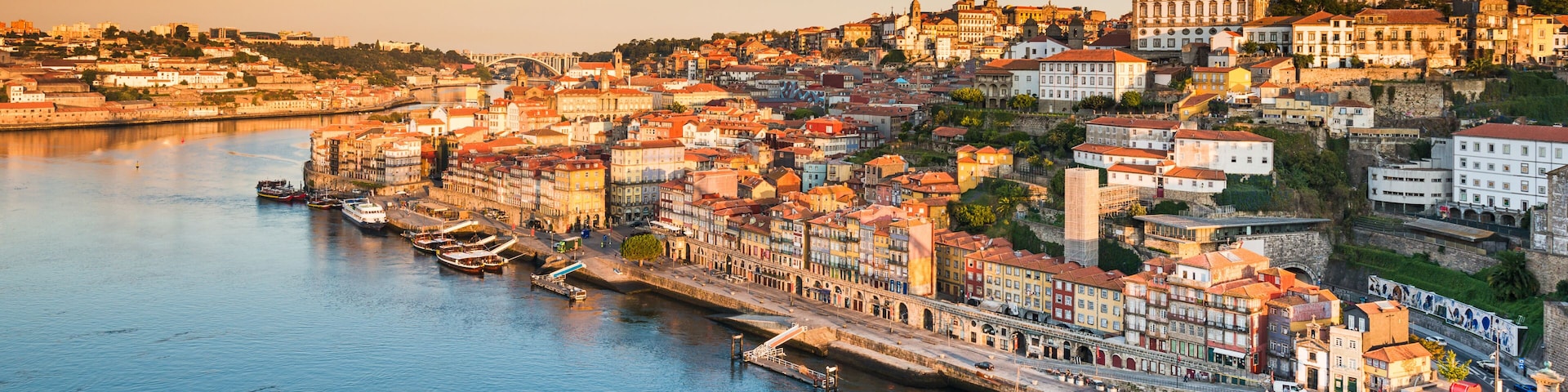 Paisagem urbana costeira com edifícios históricos, um rio e uma ponte.