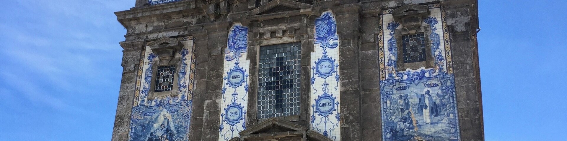 Uma igreja histórica com decorações em azulejos azuis e brancos e um campanário.