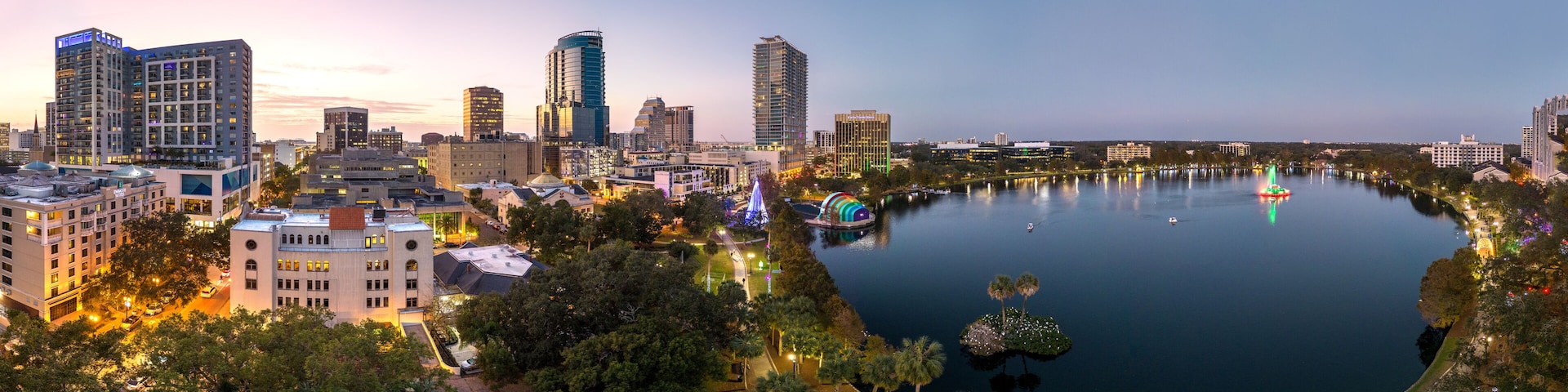 Paisagem urbana com edifícios modernos, um lago e um parque com árvores.
