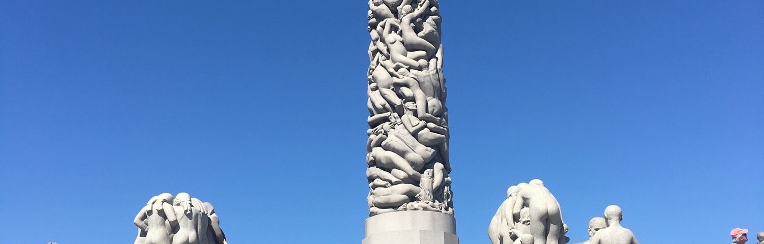 Um monumento alto com esculturas detalhadas de figuras humanas, rodeado por um conjunto de degraus de pedra.