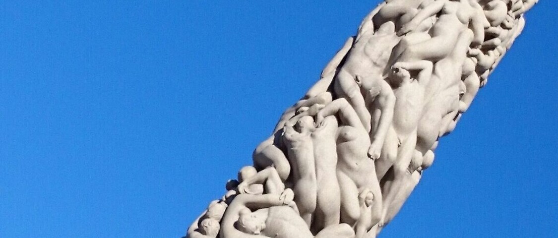 Um pilar alto, ricamente entalhado com várias figuras.