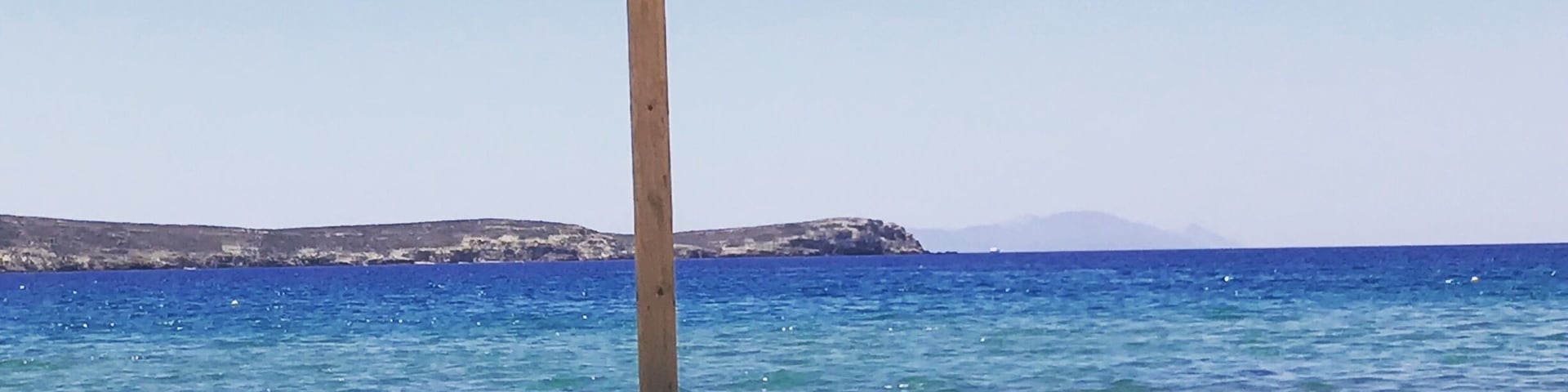 Golden Beach on the island of Paros, Greece. Big, long stretch of Beach with soft golden sand. There are big rocks in the ocean so be careful when you walk in. Water is clear so you can see down to the ocean floor. #paros #greece #beach #goldenbeach