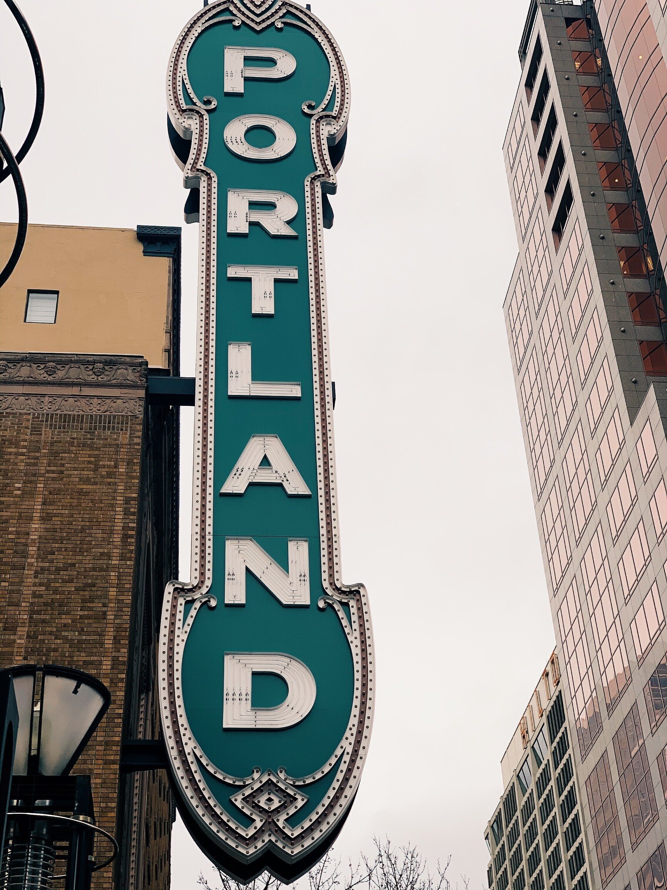 Um letreiro de neon com a palavra 'PORTLAND' em fonte estilizada, fixado em um prédio.