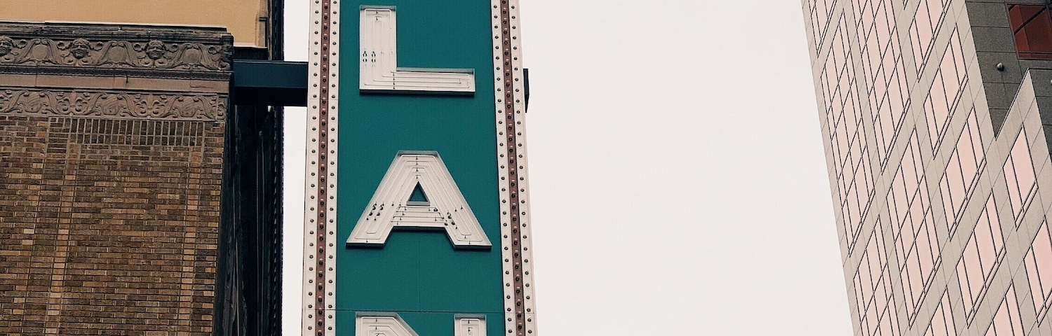 Um letreiro de neon com a palavra 'PORTLAND' em fonte estilizada, fixado em um prédio.