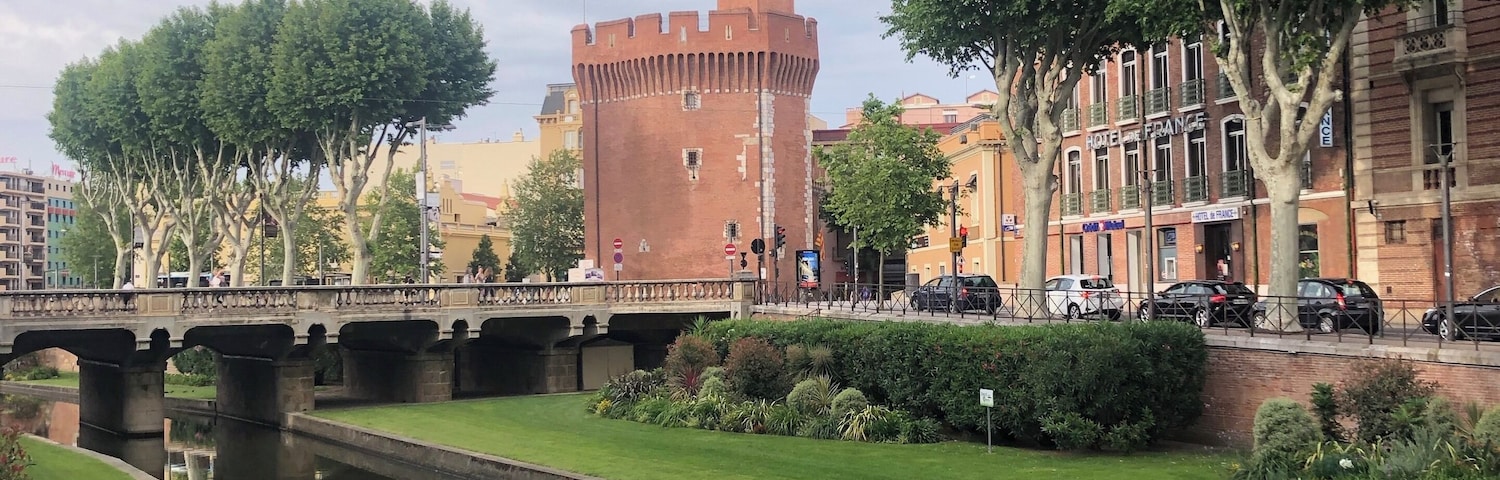Uma torre histórica, um canal e uma ponte em um horizonte urbano.