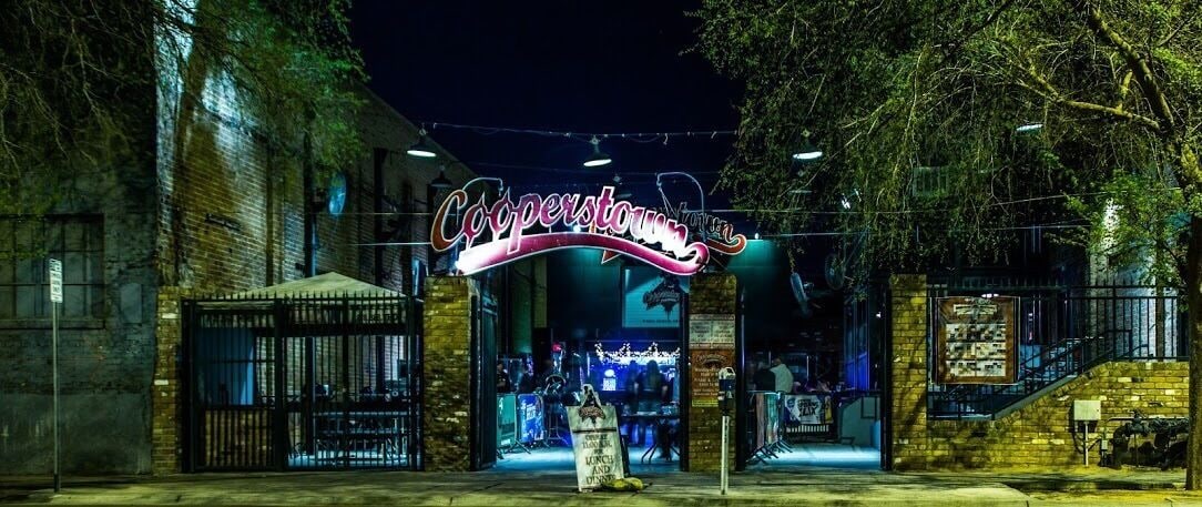 Um letreiro iluminado por neon para 'Copertown', com um edifício de tijolos e uma entrada gradeada.