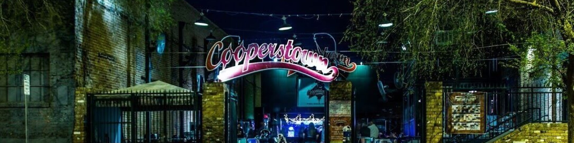 Um letreiro iluminado por neon para 'Copertown', com um edifício de tijolos e uma entrada gradeada.
