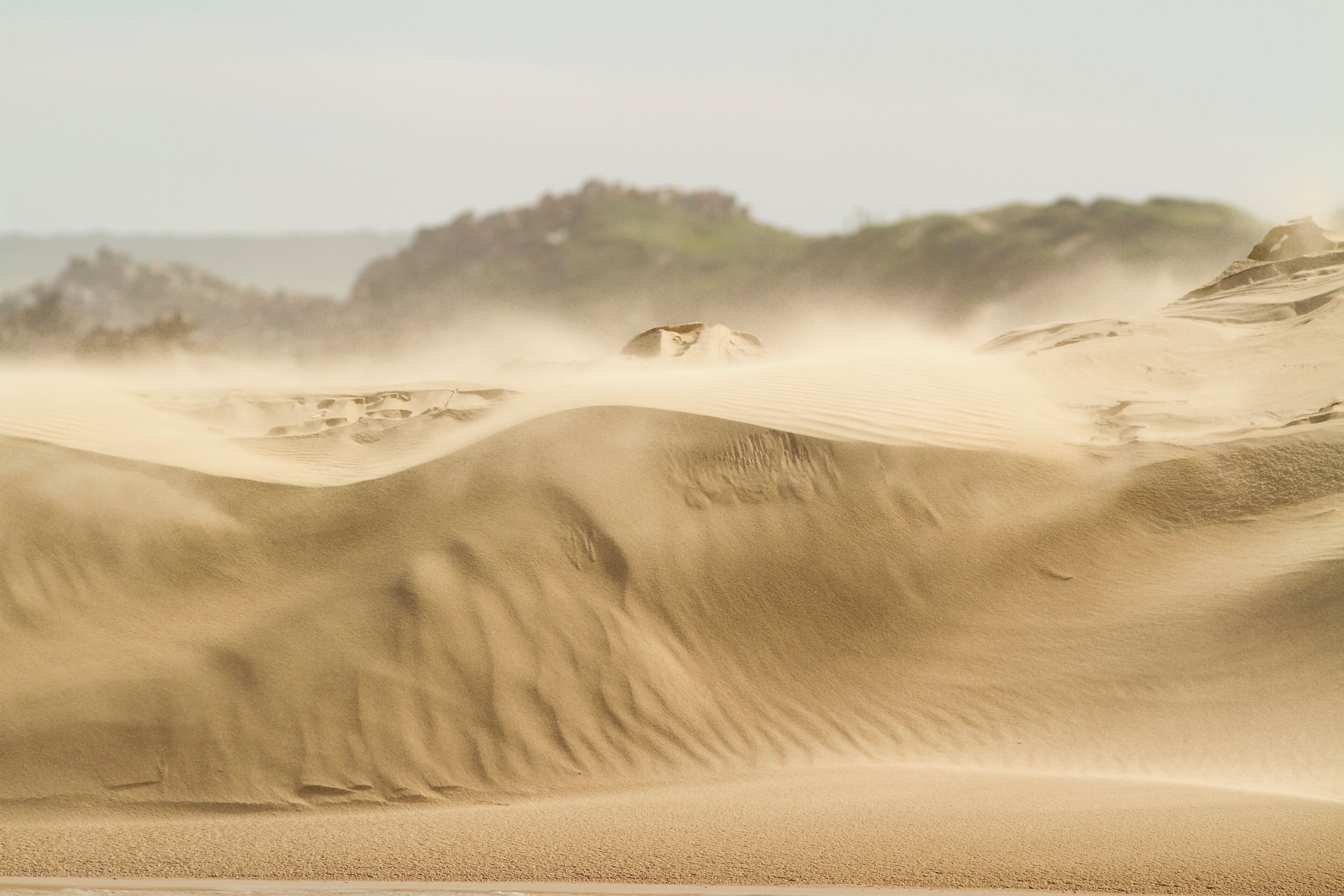 Uma duna de areia com uma colina ao fundo.
