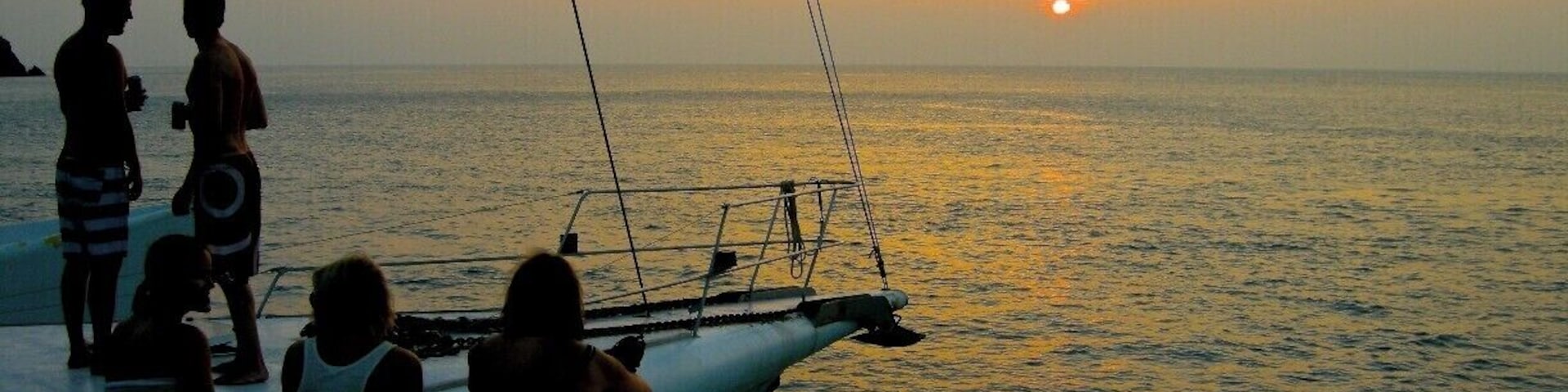 Um barco com pessoas ao pôr do sol.