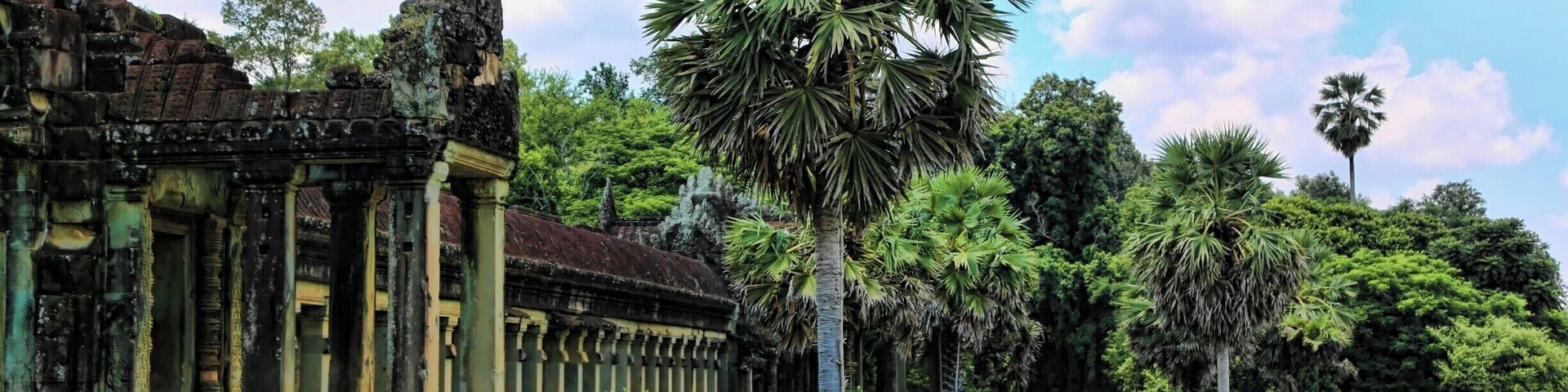 Um templo com esculturas detalhadas e uma palmeira imponente ao primeiro plano.