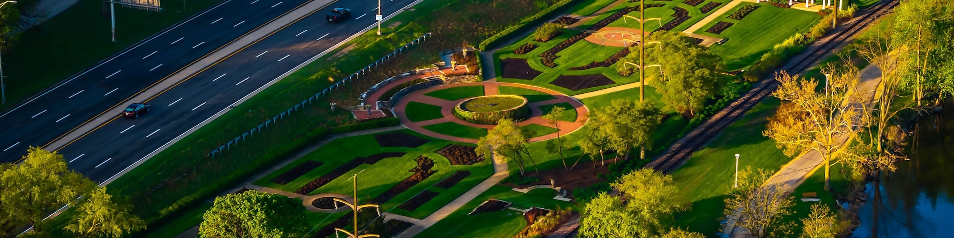 Vista aérea de uma área ajardinada com uma estrada, uma fonte e um gazebo.