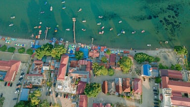 Vista aérea de uma cidade costeira com barcos, edifícios coloridos e um mar azul límpido.
