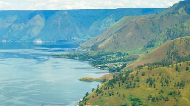 Vista panorâmica de um lago rodeado por colinas e montanhas verdes.