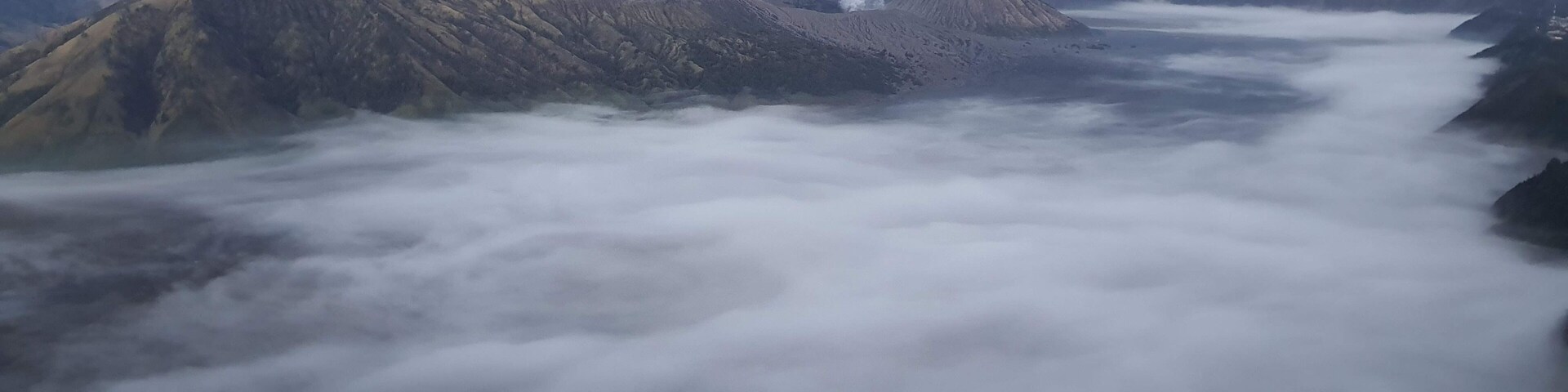 Paisagem montanhosa com um vale envolto em nuvens.