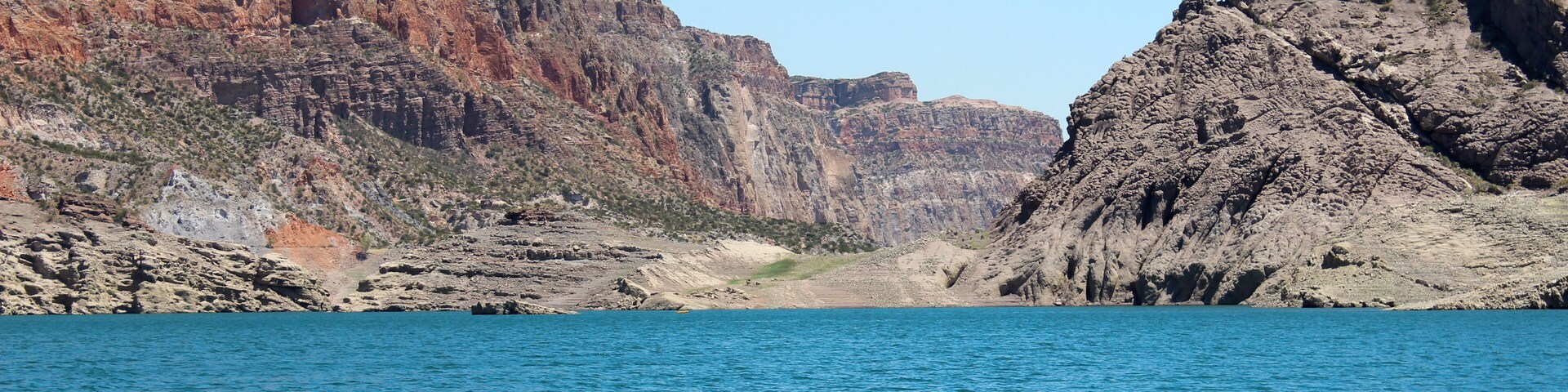 Um cânion com penhascos íngremes e um rio azul calmo.
