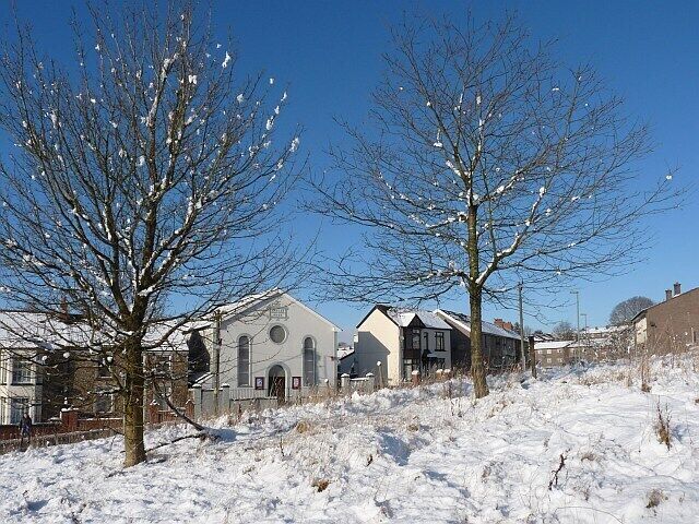 Paisagem coberta de neve com árvores sem folhas e uma igreja.