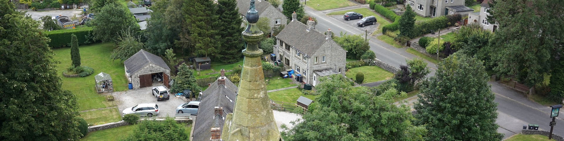 Uma vila com uma imponente torre de igreja, casas residenciais e uma grande estátua dourada de galo.