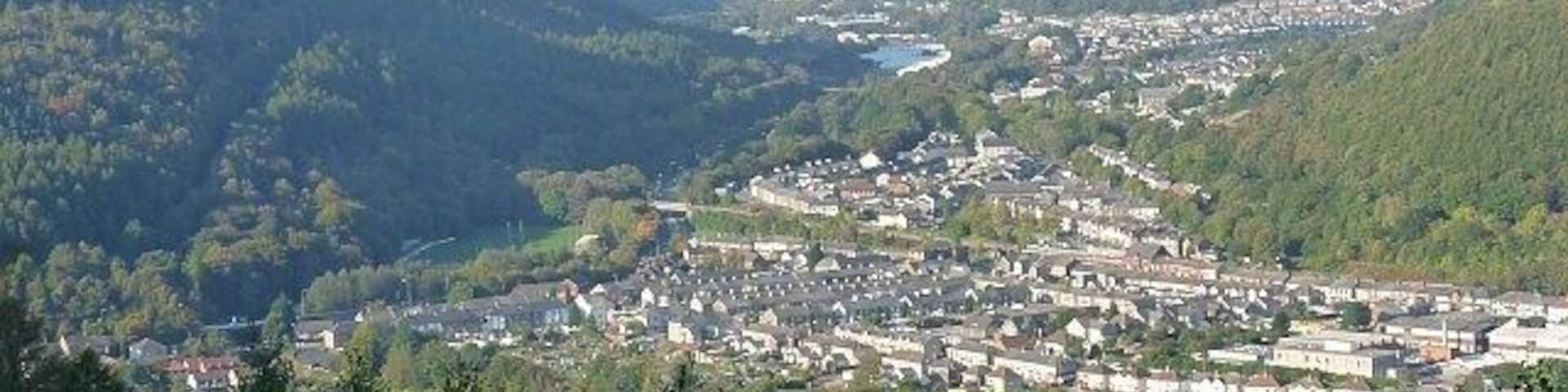 View of Crosskeys and the Ebbw Valley. Taken from the edge of Mynydd Machen Common 1577238. The River Ebbw flows down the valley in the centre of the view towards the left centre and then bends to the right towards Risca. The River Sirhowy flows down the valley on the left and joins the River Ebbw by the recreation ground in the lower right. The lower end of the Cwmcarn Valley is at the upper right.