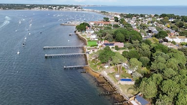 Vista aérea de uma vila costeira com um porto, casas e um cais.