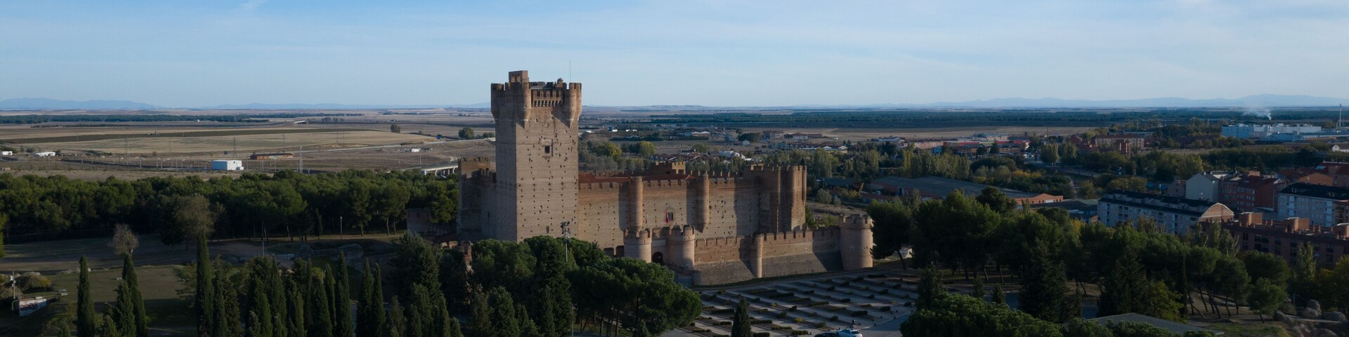 Um castelo medieval rodeado por árvores e uma pequena vila.