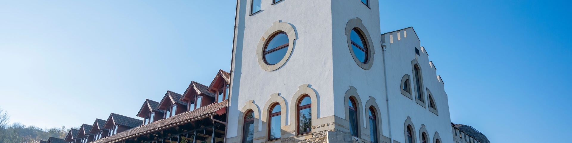 Um edifício histórico com uma torre, janelas em arco e fachada de pedra.