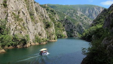 Um barco em um rio, cercado por penhascos íngremes.