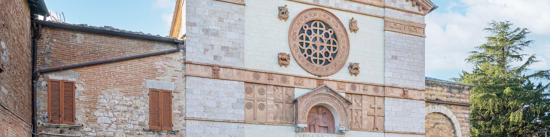 Uma igreja histórica com uma grande janela circular, entrada em arco e detalhadas esculturas na fachada.