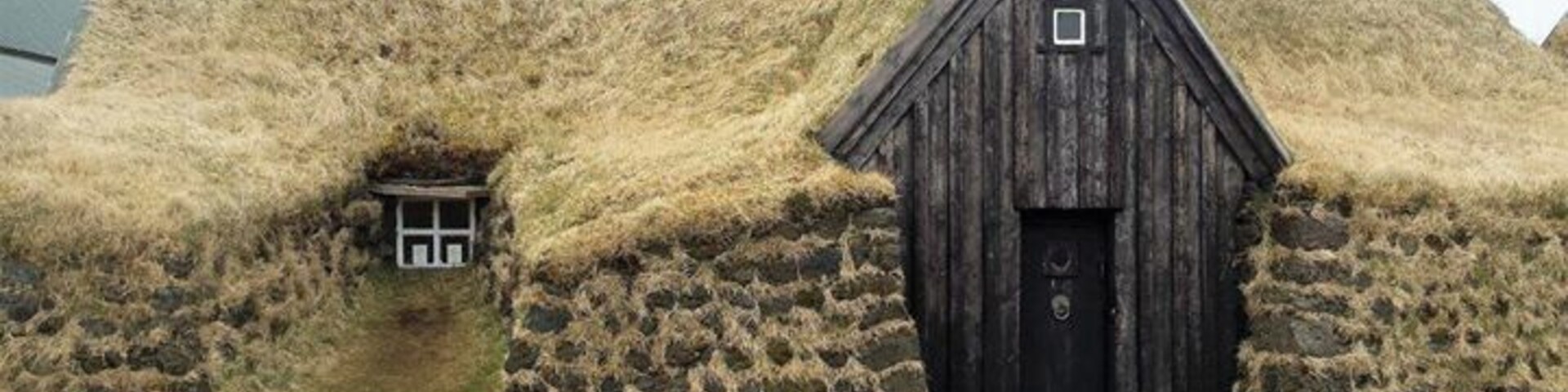 Uma casa tradicional de turfa com parede de pedra e porta de madeira.
