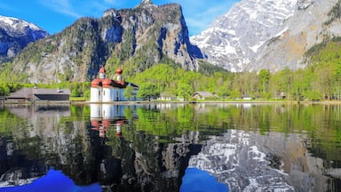 Um lago de montanha com uma igreja e edifícios refletidos na água.