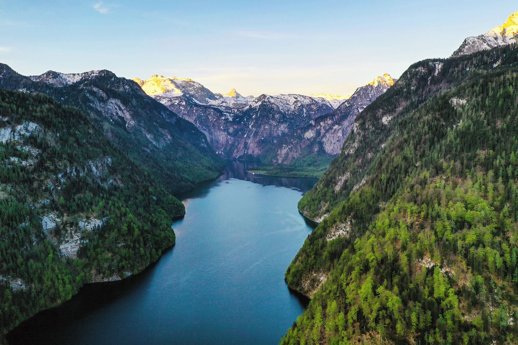 Um vale com um lago rodeado por montanhas florestadas.