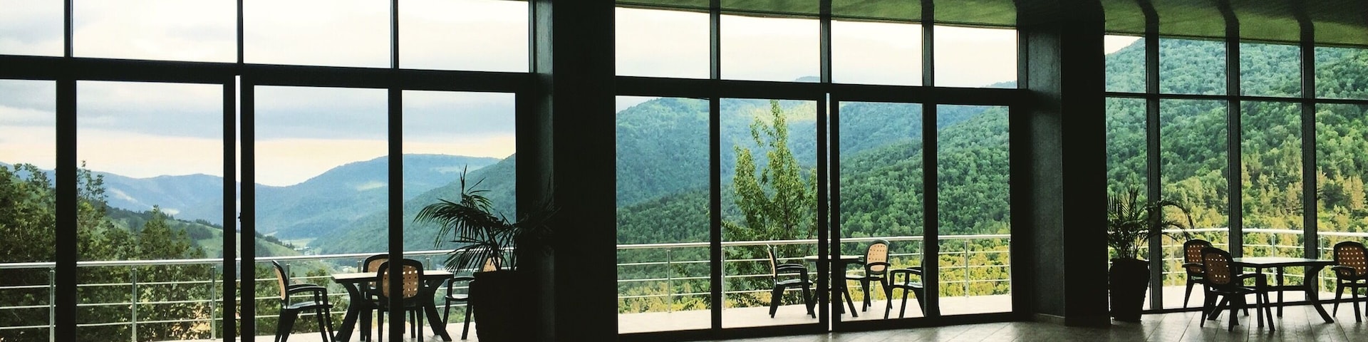 Amplo espaço interno com grandes janelas que oferecem vista para uma paisagem montanhosa.