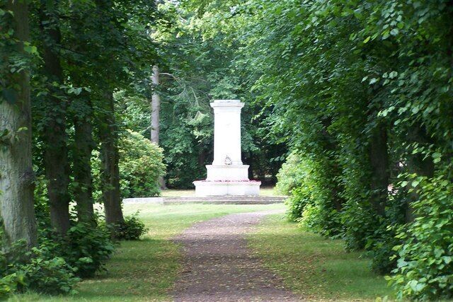 Um monumento branco num parque rodeado de árvores.