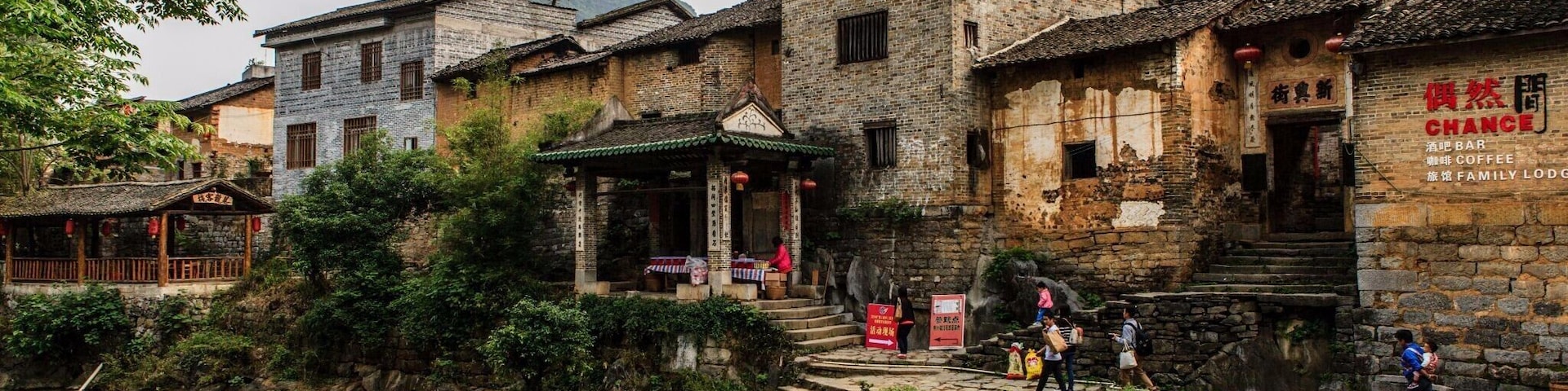 Uma aldeia tradicional com edifícios de pedra, um rio e uma montanha ao fundo.