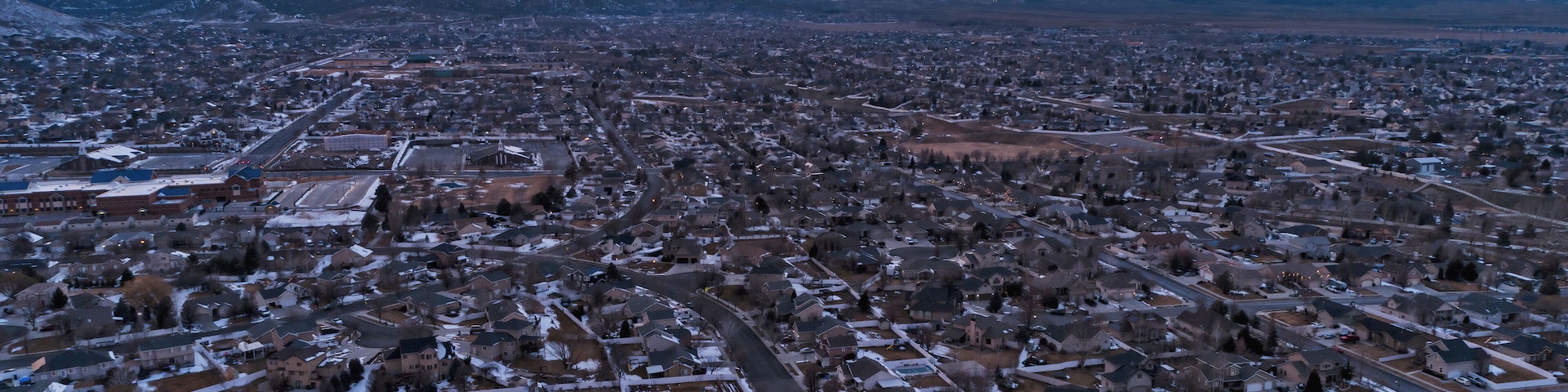 Uma cidade coberta de neve com montanhas ao fundo.