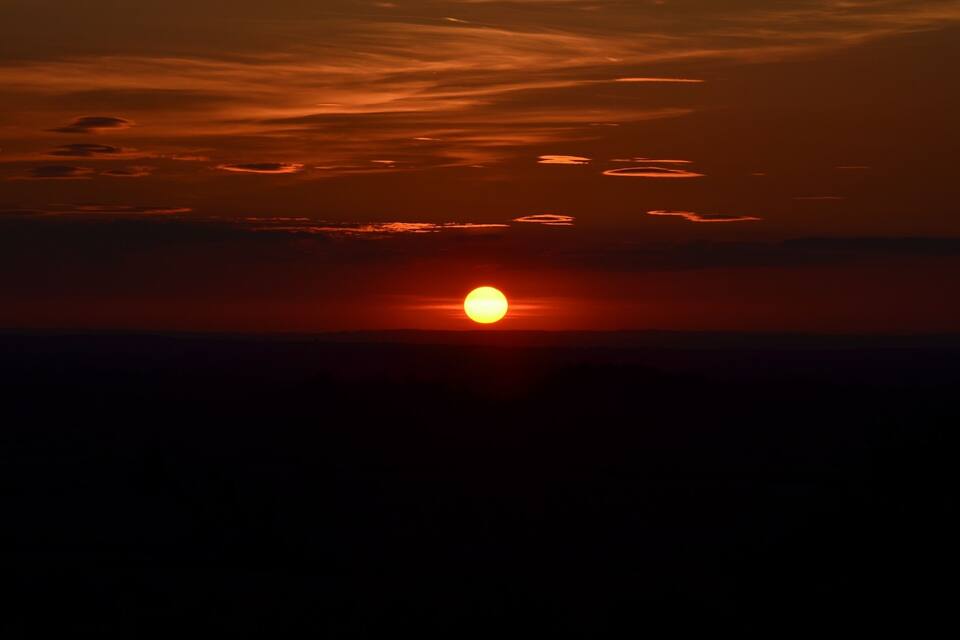 Pôr do sol com o sol visível e nuvens no céu.